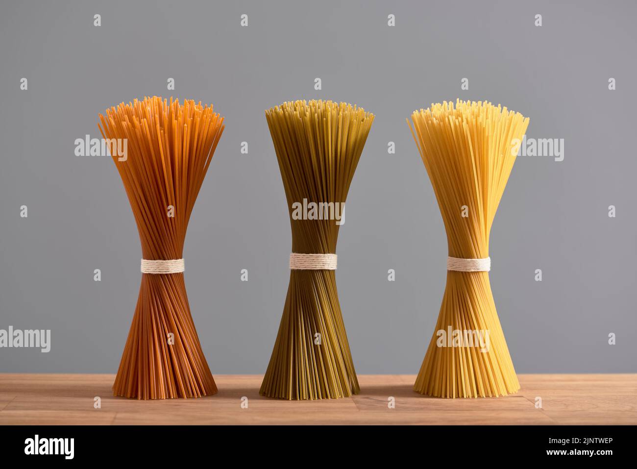 Pasta, three bunches of raw spaghetti of different colors on a wooden ...