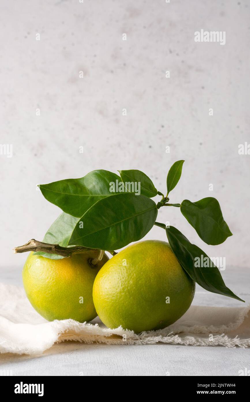 sweet orange fruits with its leaves, placed on white surface with cloth ...