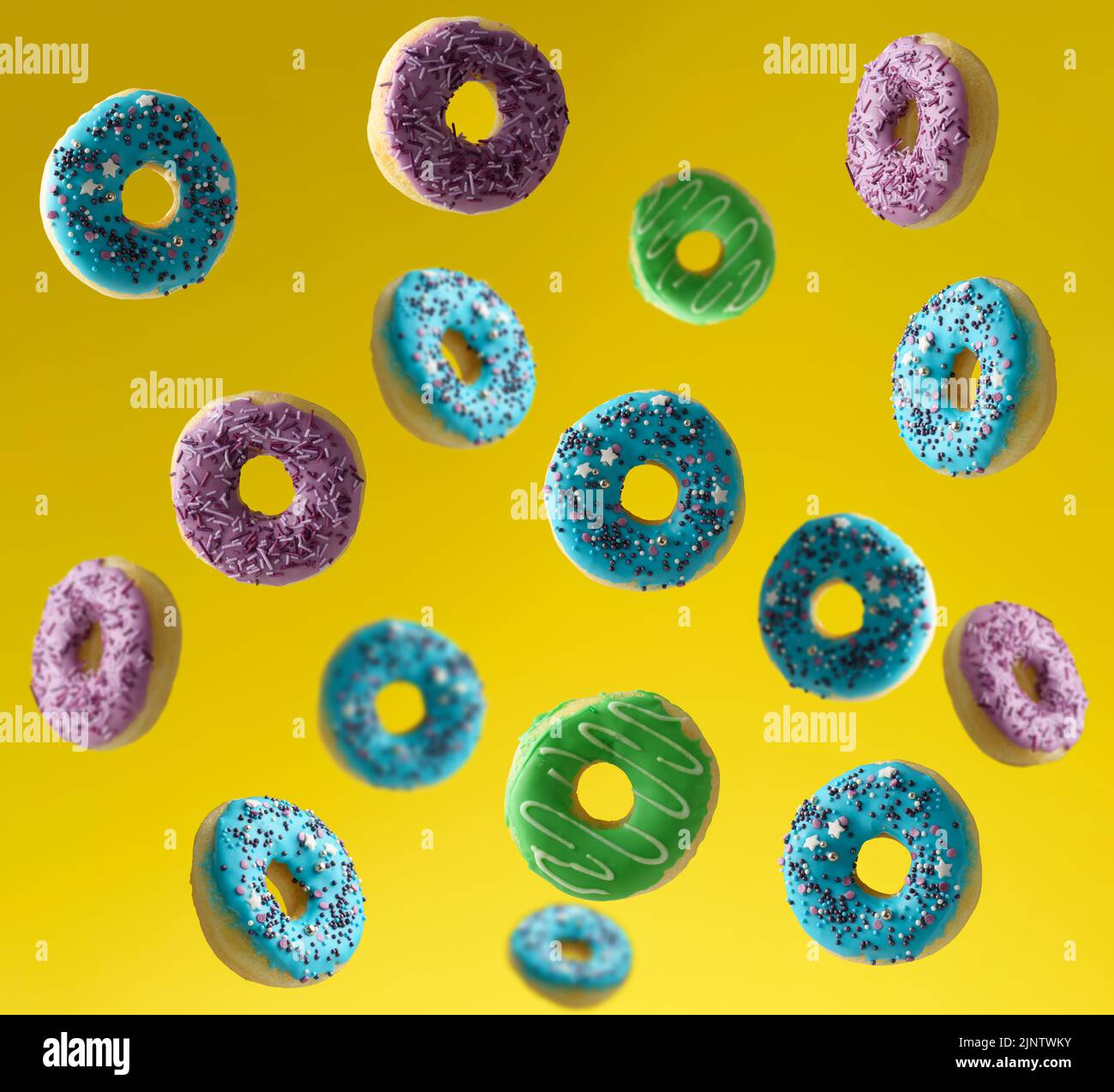 Multi-colored donuts sprinkled with sugar sprinkles fly on a yellow ...