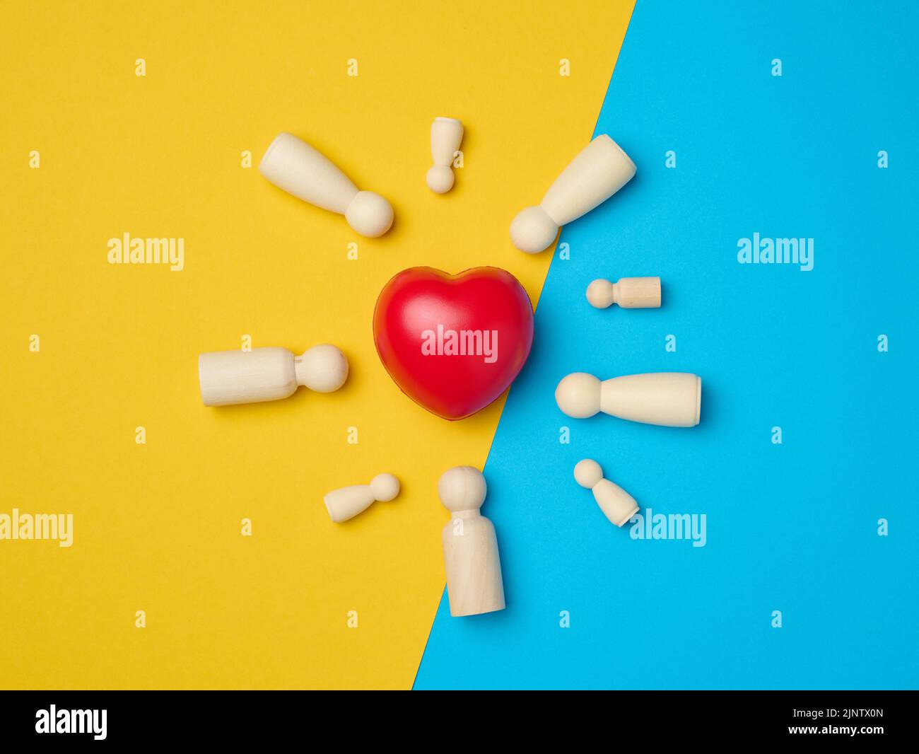 Red heart and wooden figurines of men on a yellow-blue background, top ...