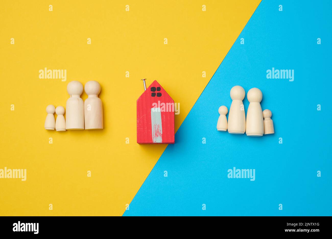 Wooden figures of men and a miniature house on a beige background. The ...