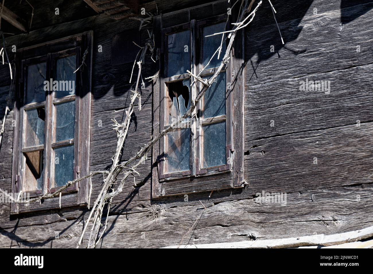 Two windows with broken windows at an old uninhabited wooden house ...