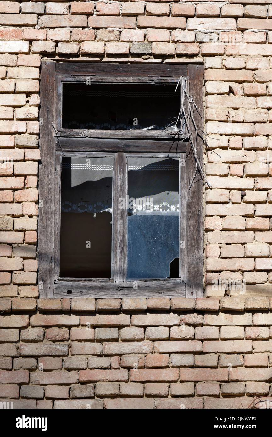 Detail of an old abandoned house with broken window panes, with a brick ... Detail of an old abandoned house with broken window panes, with a brick ...