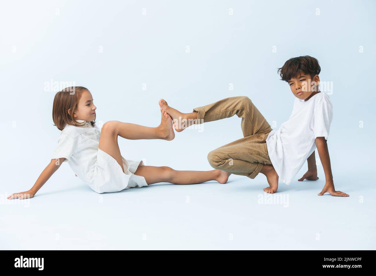 Funny boy and girl pressing feet against one another's on the floor ...