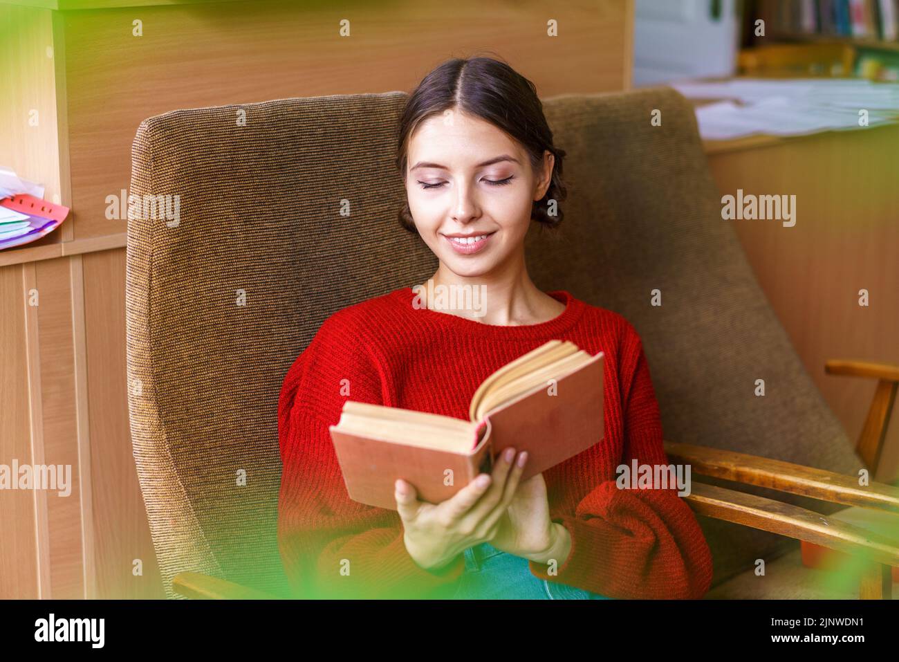 View gorgeous young woman with an interesting book in her hands. She is ...