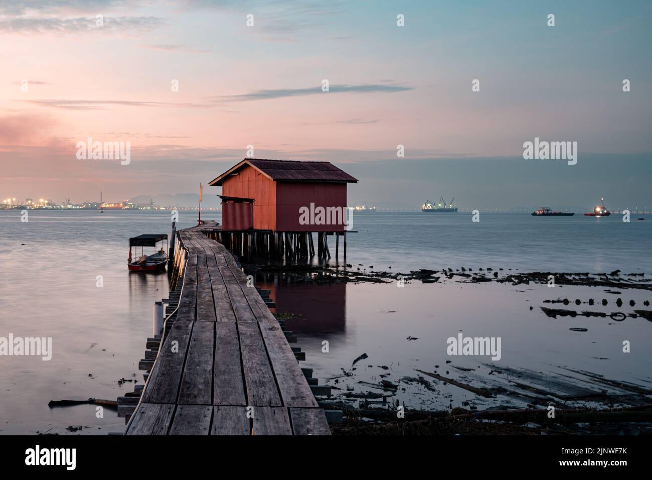 Sunrise view of wooden bridge and red house background at Clan Tan Jetty, one of tourist spots ...