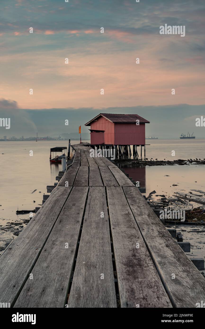 Sunrise view of wooden bridge and red house background at Clan Tan Jetty, one of tourist spots ...
