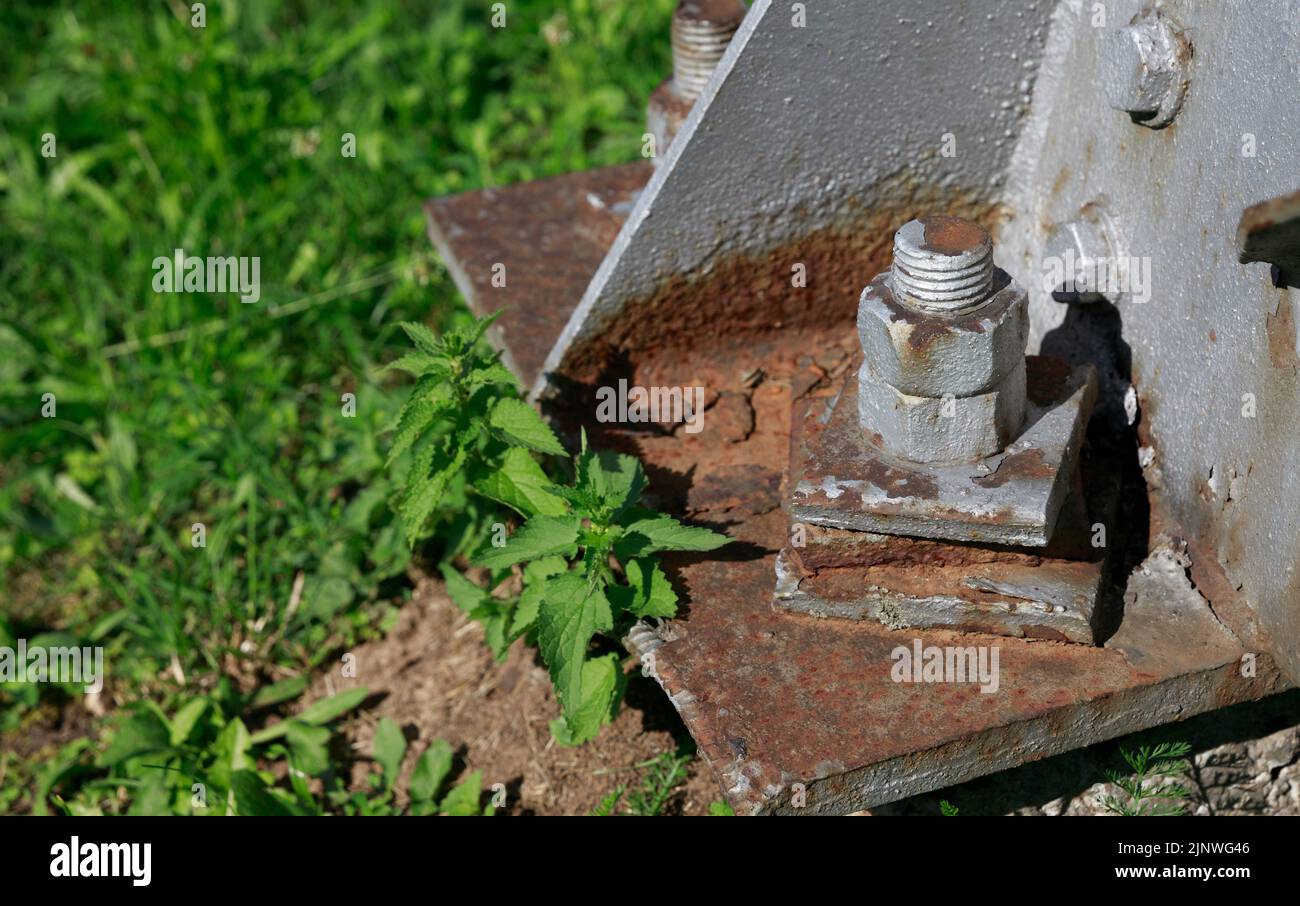 On the rusty metal base of the column, a rusty bolt is firmly attached ...