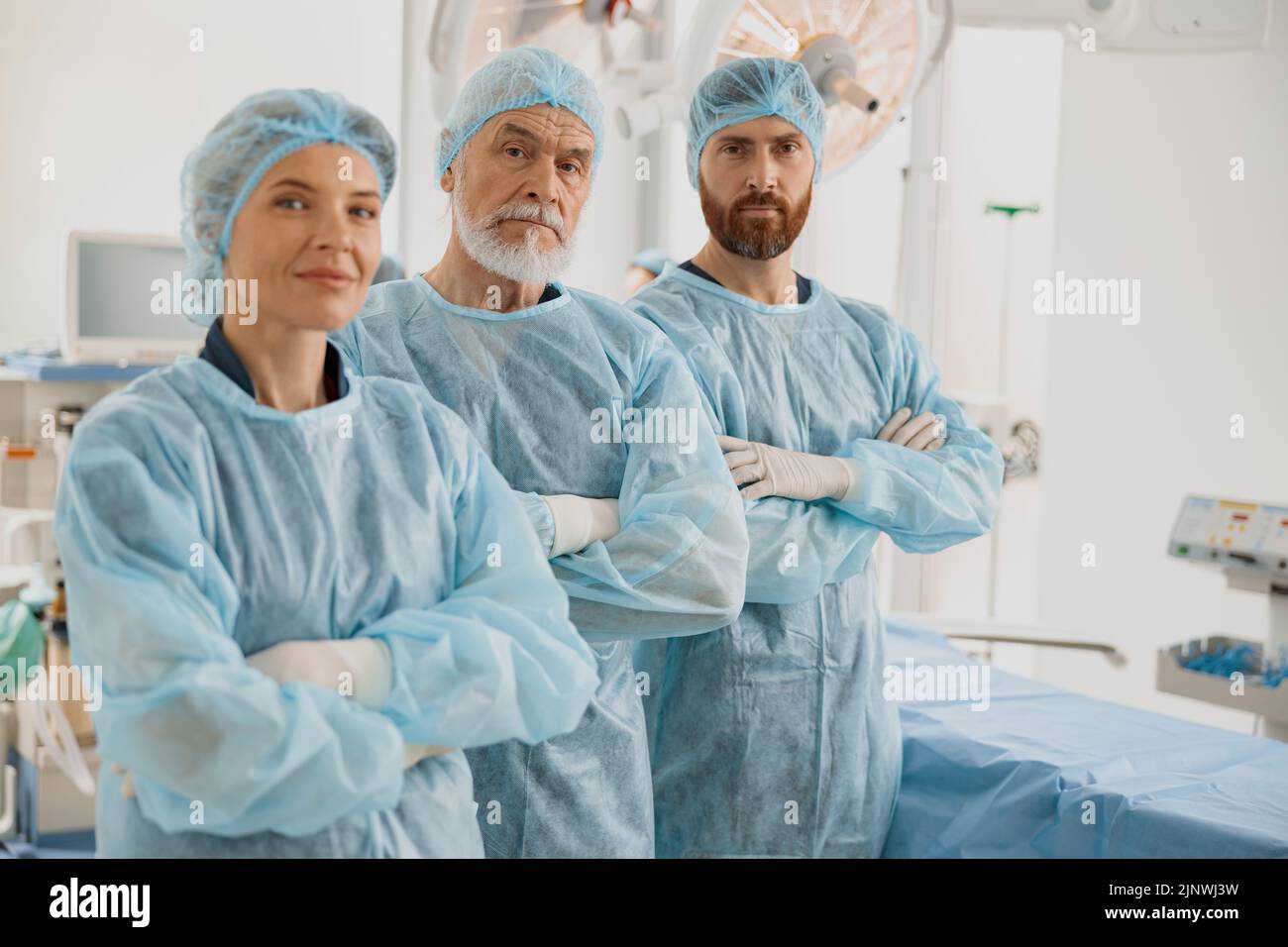 Team of professional surgeons with crossing hands standing in operating ...