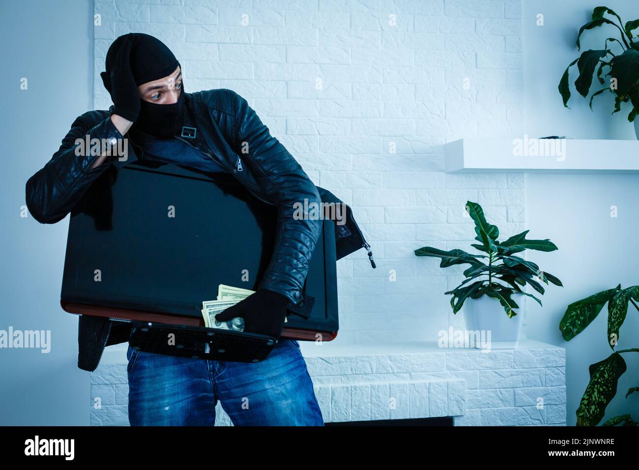 Robber man dressed in black hoodie stands with disguised face and holds ...