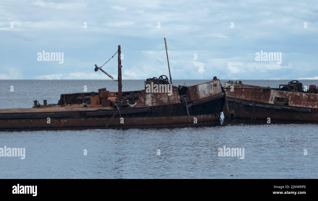 Two old rusty abandoned barges standing nose to nose on the water ...