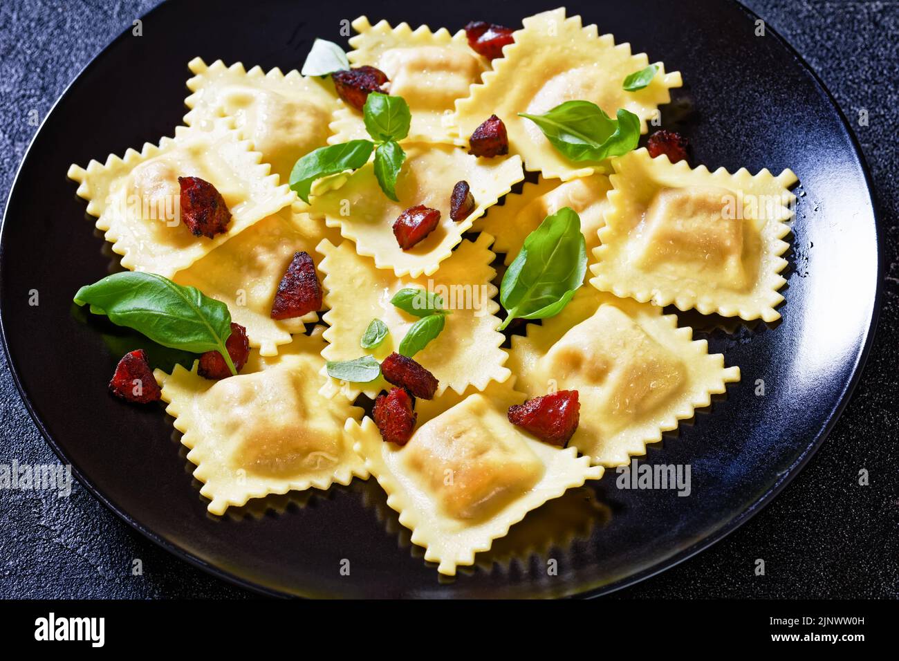 italian ravioli with chorizo ricotta filling served on black plate with ...