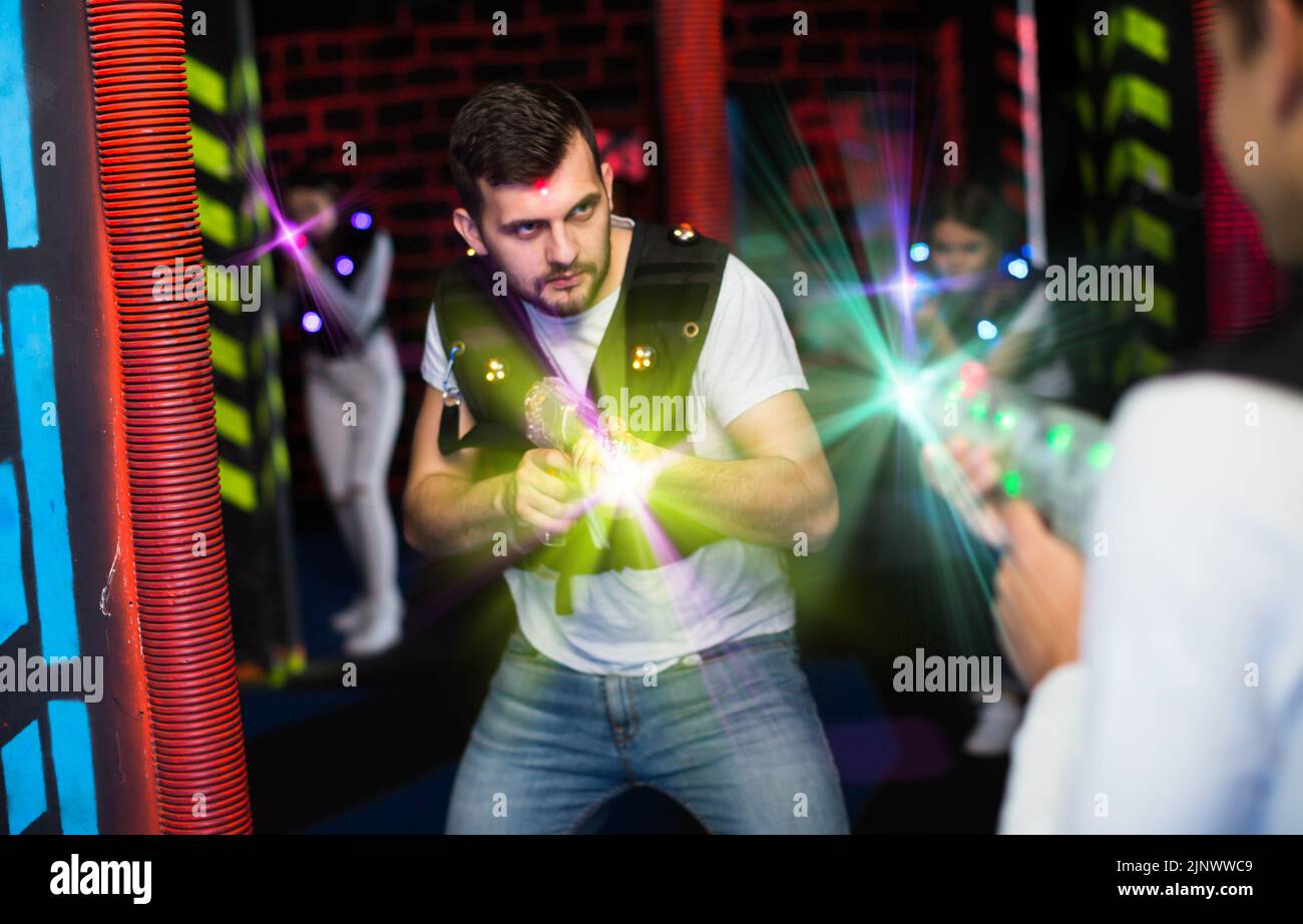 Emotional guy playing laser tag in colorful beams Stock Photo - Alamy