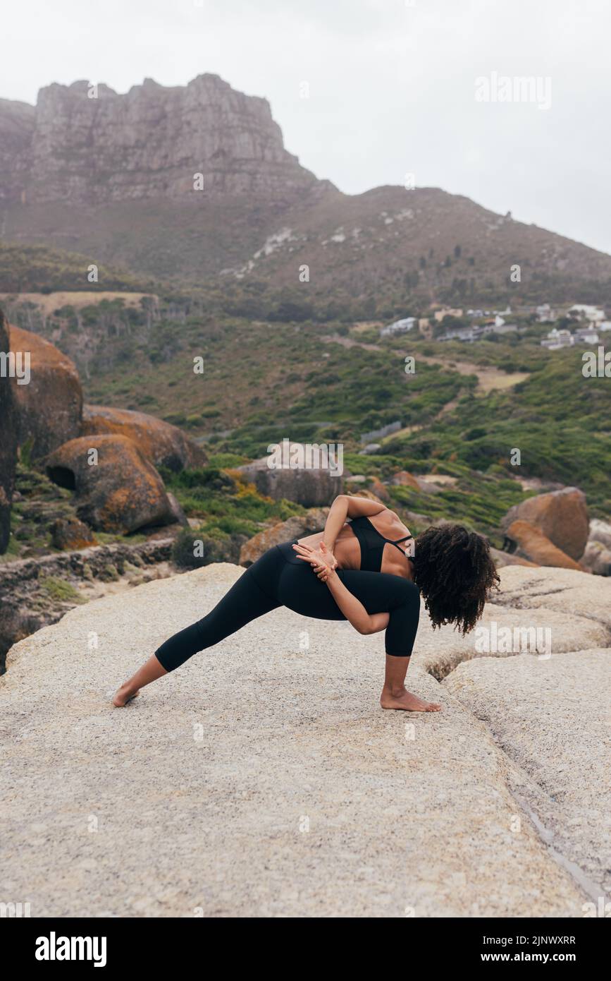 Back view of flexible slim female standing on mat and performing bound ...