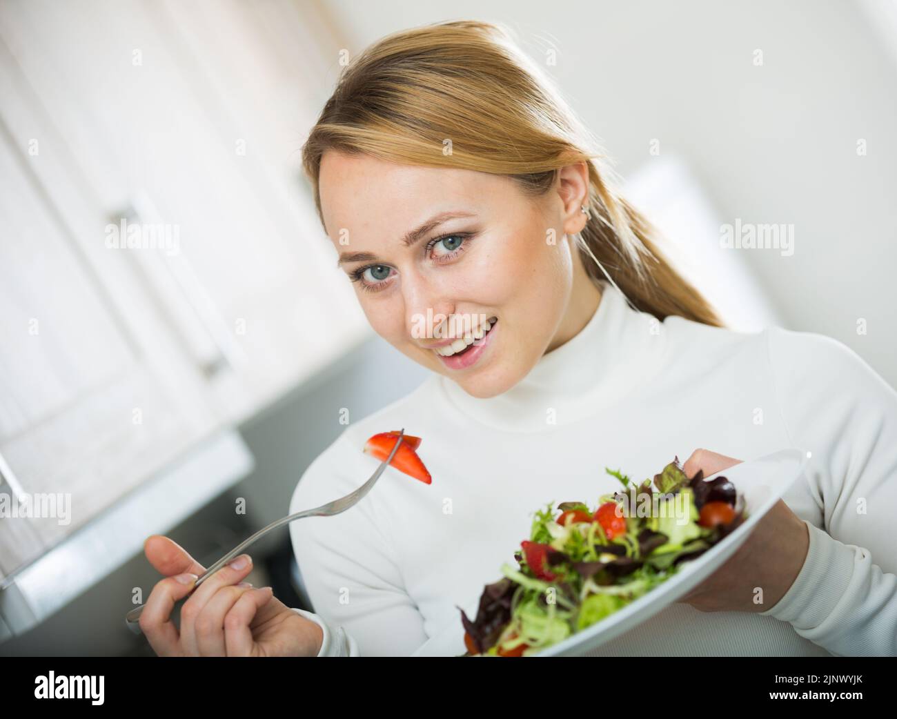 Cheerful blond girl eating salad Stock Photo - Alamy