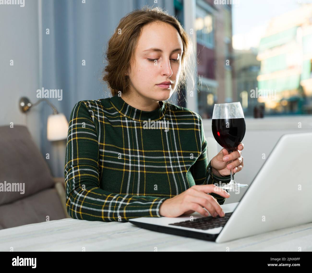 Girl using laptop drinking wine Stock Photo - Alamy