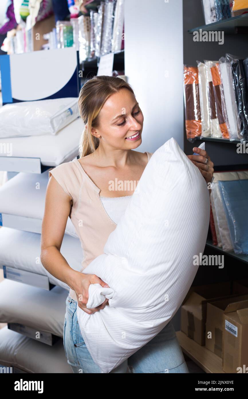 Cheerful smiling woman choosing downy pillow Stock Photo - Alamy