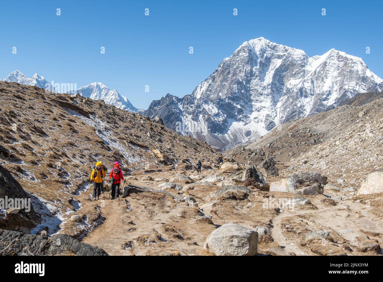 Tourist and porters walking on dirt road in Nepal to Everest Base Camp ...