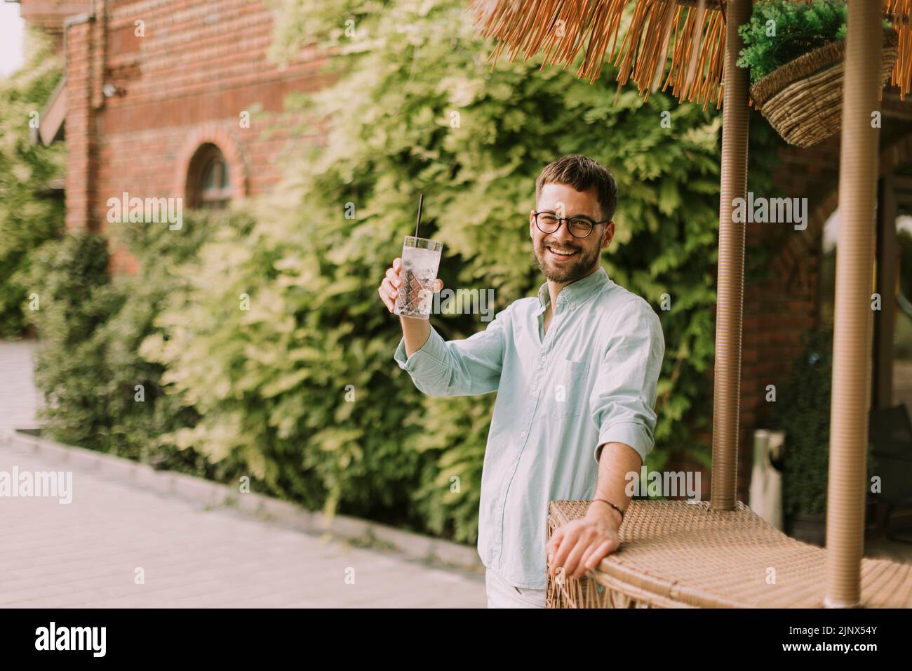Handsome young man drinking fresh cold lemonade at the pool bar Stock ...