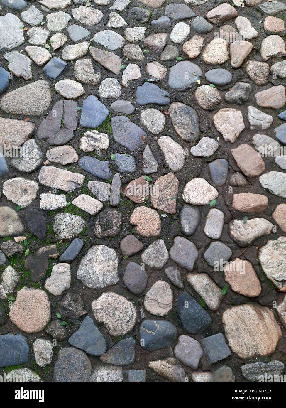 A fragment of a wall made of rough stones of different colors and sizes ...