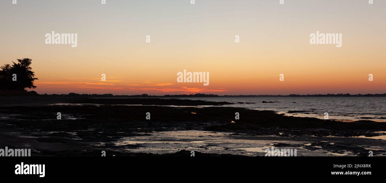Panorama of the sunrise at high tide with the beach the rocks and the ...
