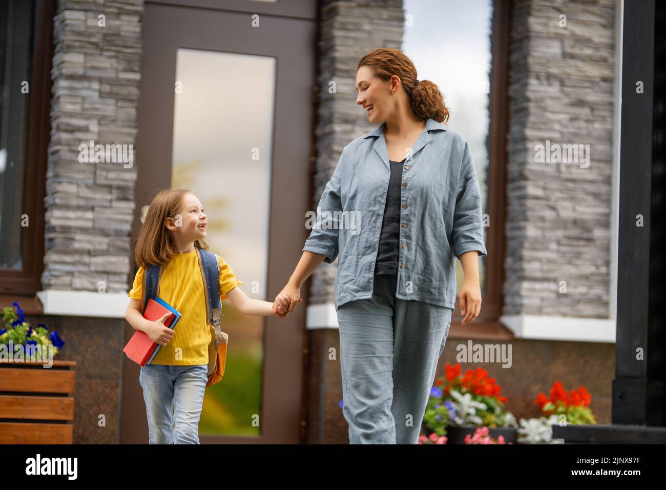 Parent and pupil of primary school going hand in hand. Woman and girl ...