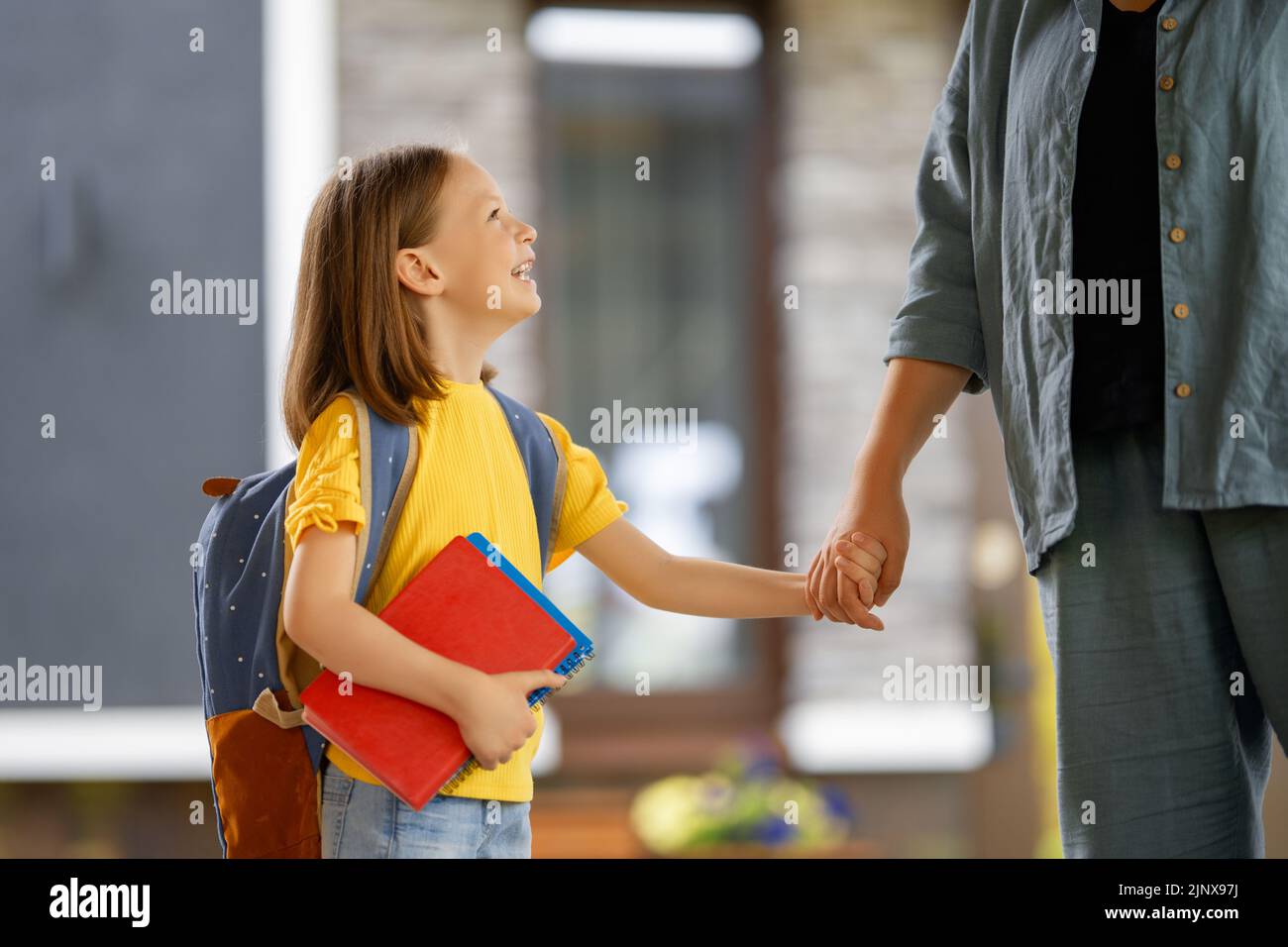 Parent and pupil of primary school going hand in hand. Woman and girl ...