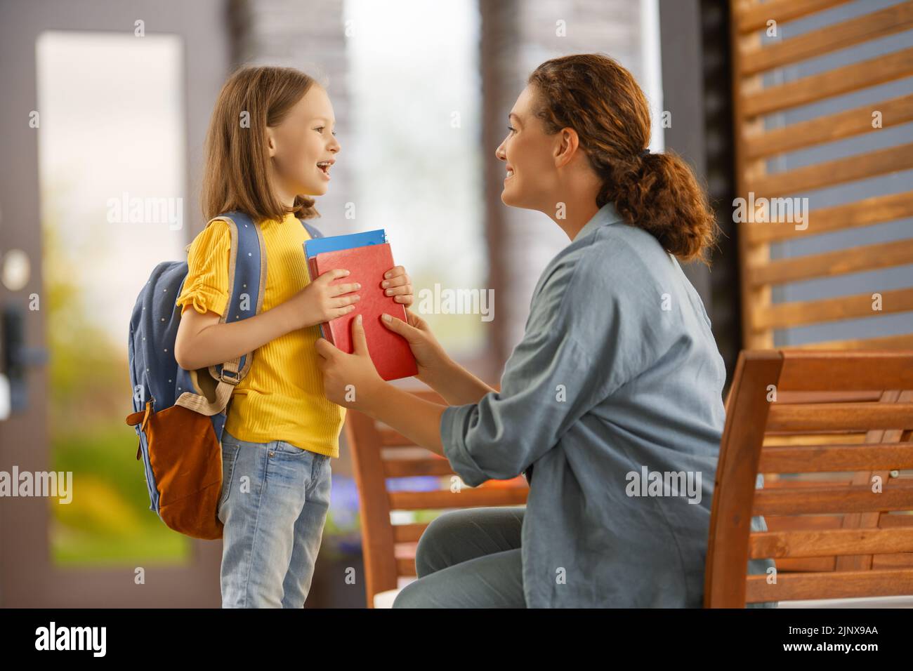 Parent and pupil of primary school going hand in hand. Woman and girl ...
