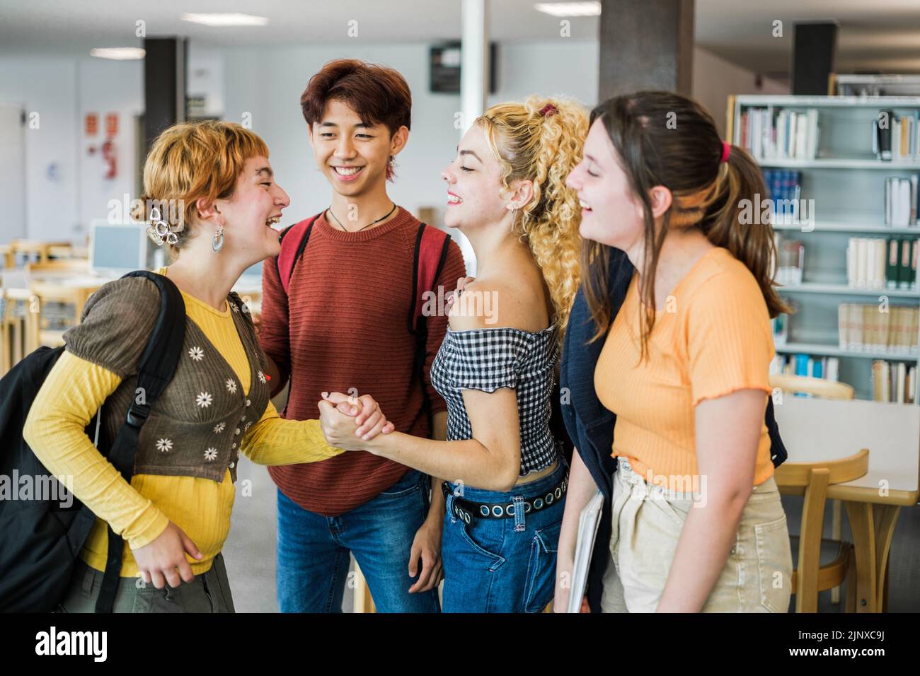 Small group of students greeting each other in the university library ...