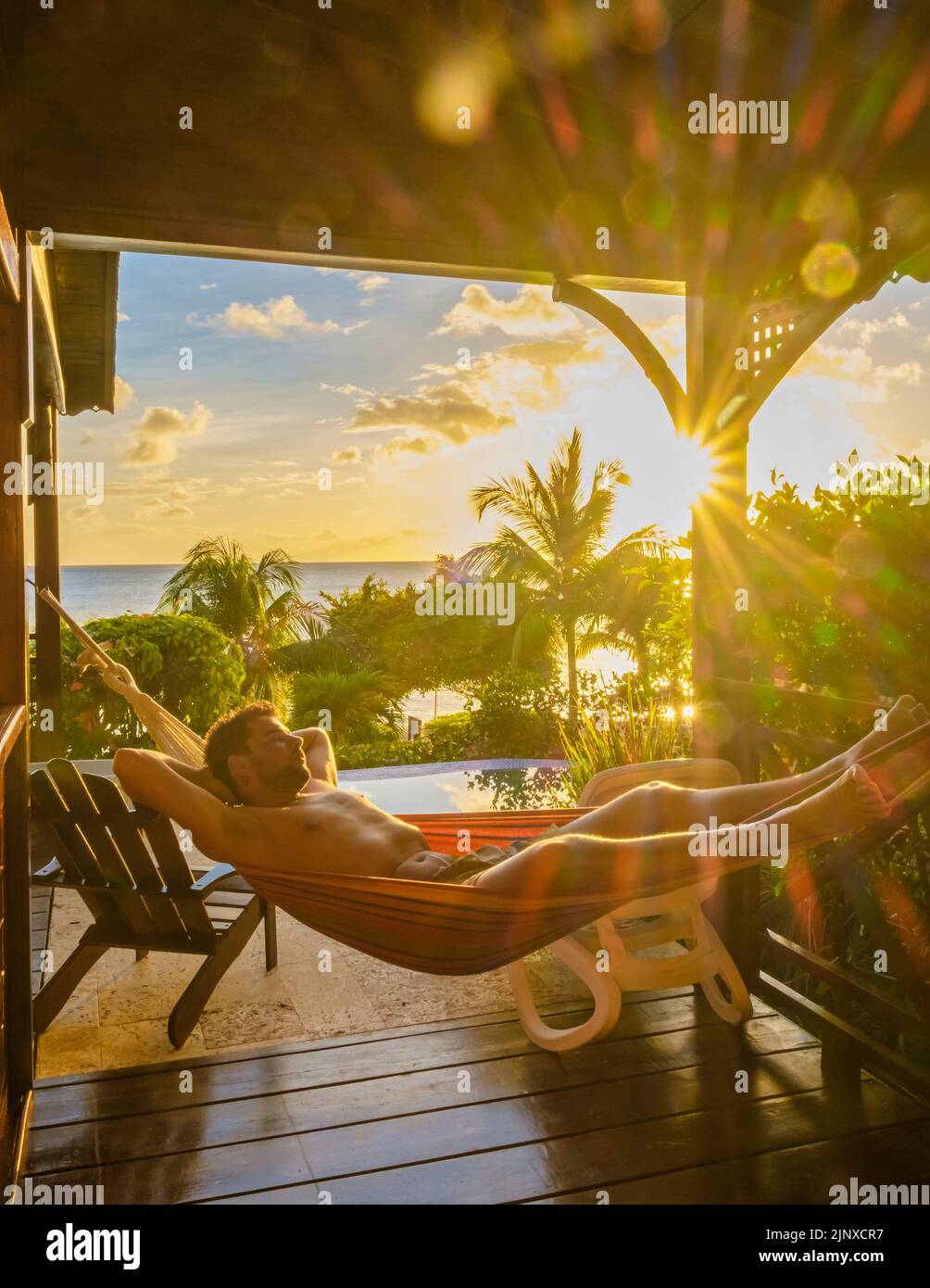 Young men in swim shorts sunbathing in a hammock at Saint Lucia ...