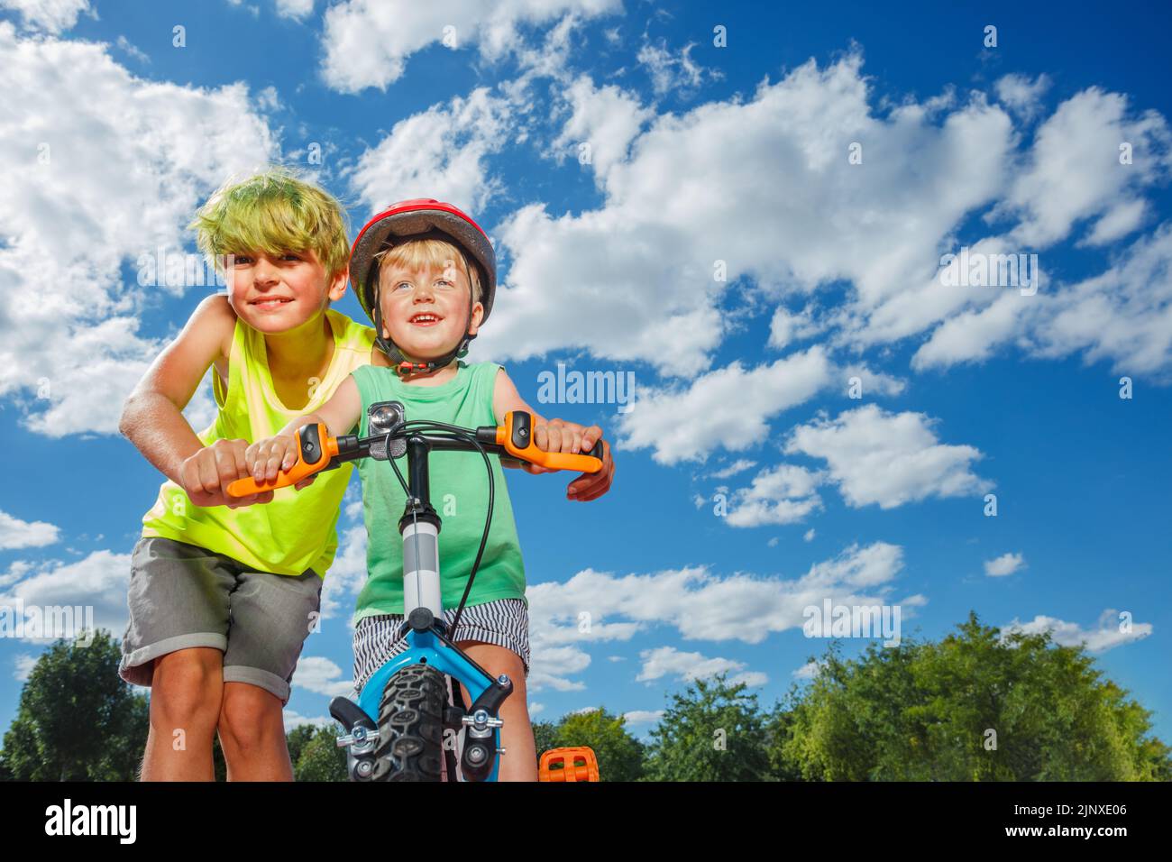 Close-up photo: big brother help little boy ride a small bicycle Stock ...