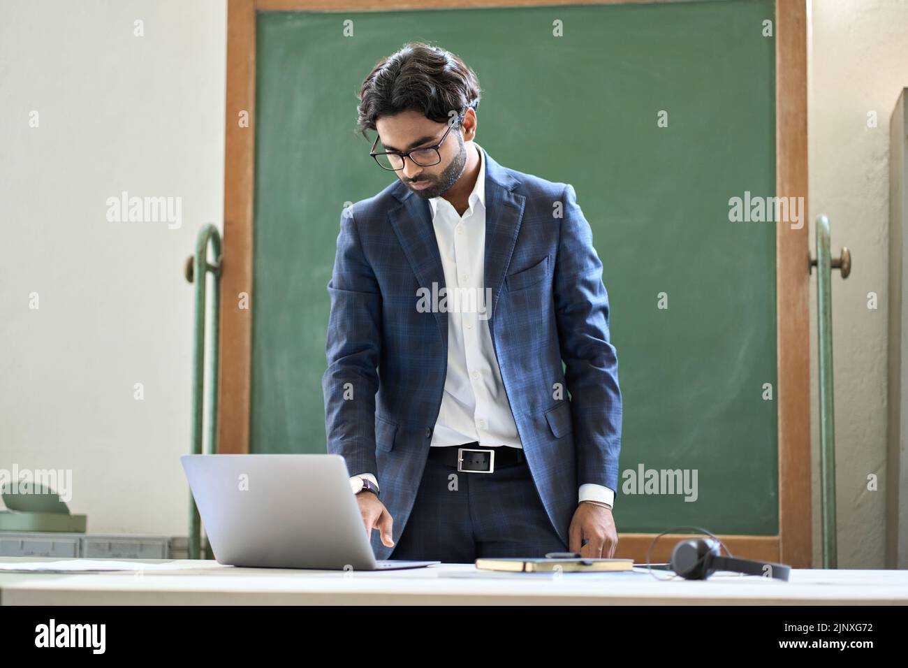 Young indian business man working on laptop computer standing in office ...
