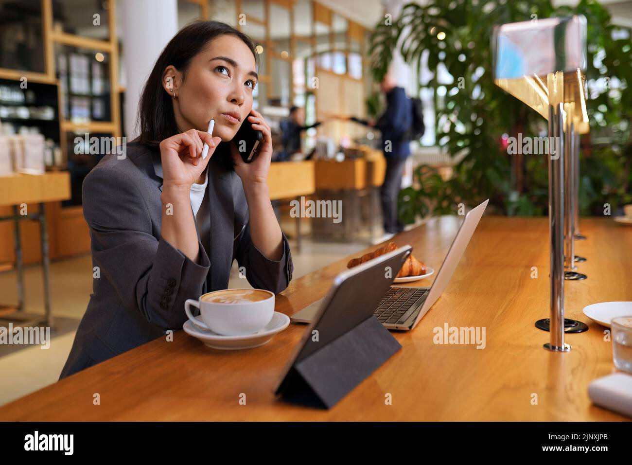Doubtful Asian business woman talking on phone making call and thinking ...