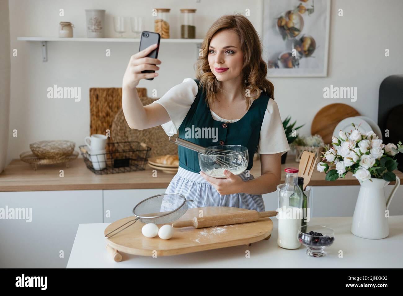 Beautiful girl cooks and looks at the recipe on the smartphone Stock ...