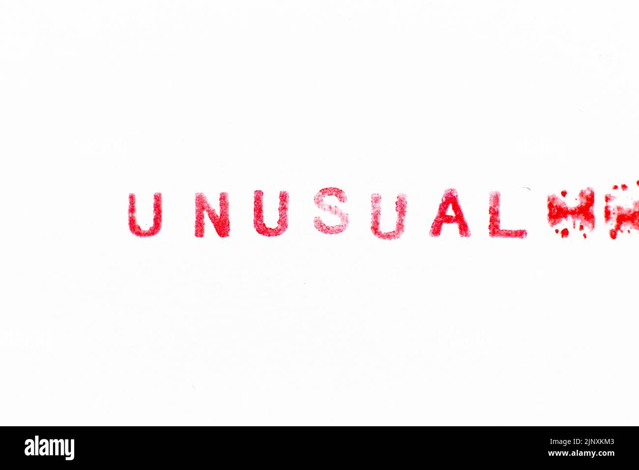 Red color ink rubber stamp in word unusal on white paper background ...
