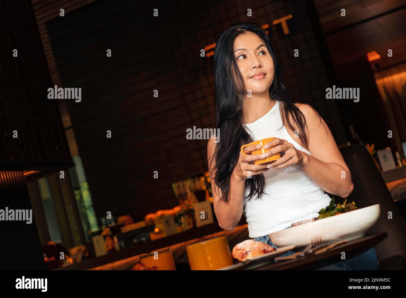 Smiling asian woman drinking a coffee in a restaurant or coffee shop Stock Photo - Alamy