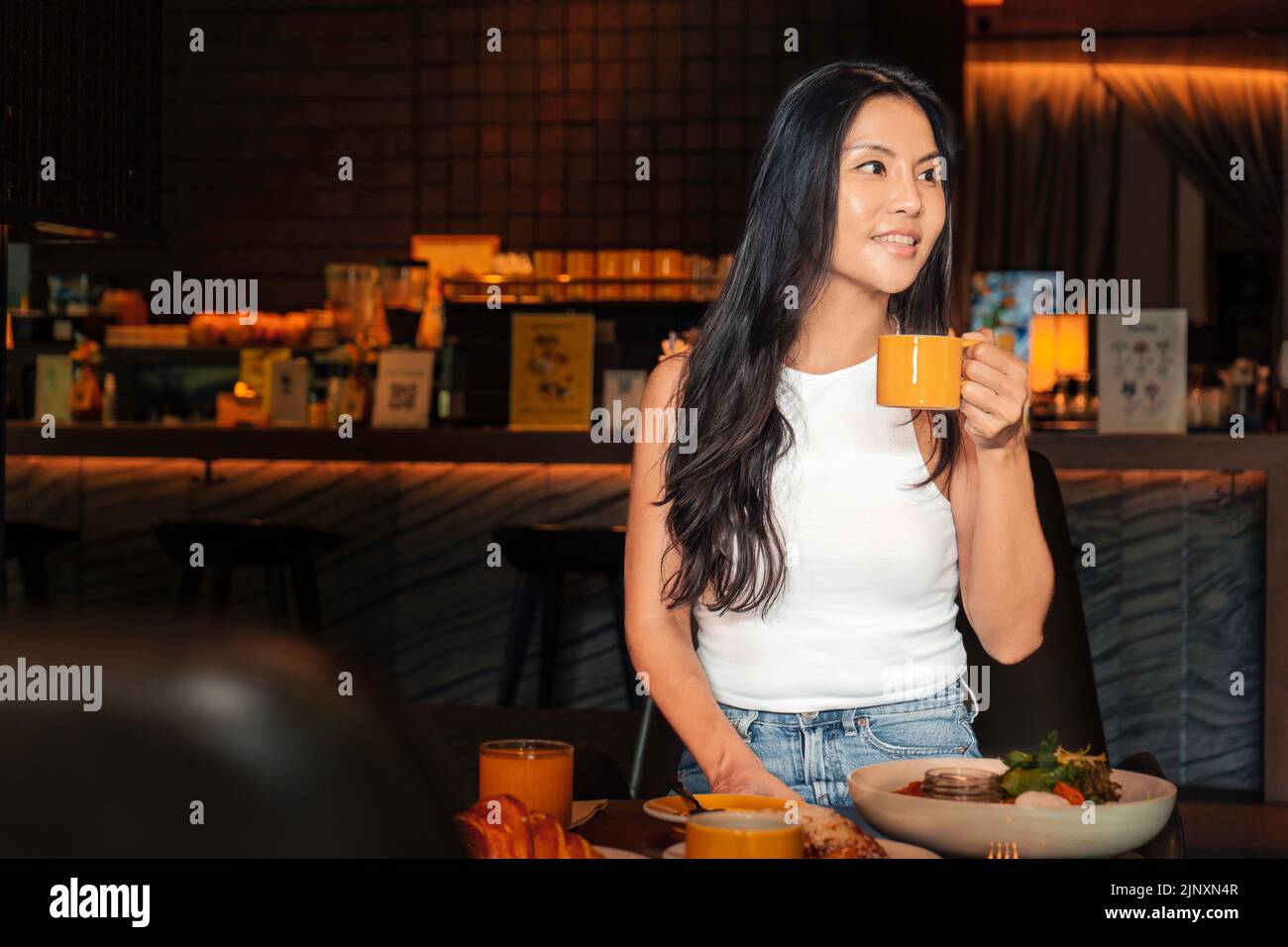 Smiling asian woman drinking a coffee in a restaurant or coffee shop Stock Photo - Alamy