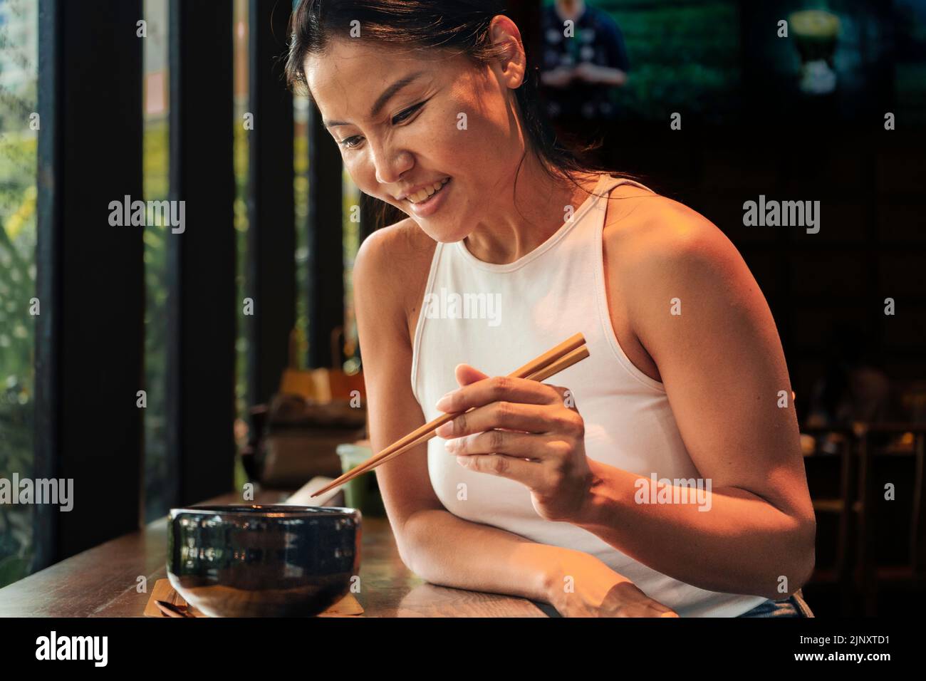Smiling beautiful asian woman eating with chop sticks Stock Photo - Alamy