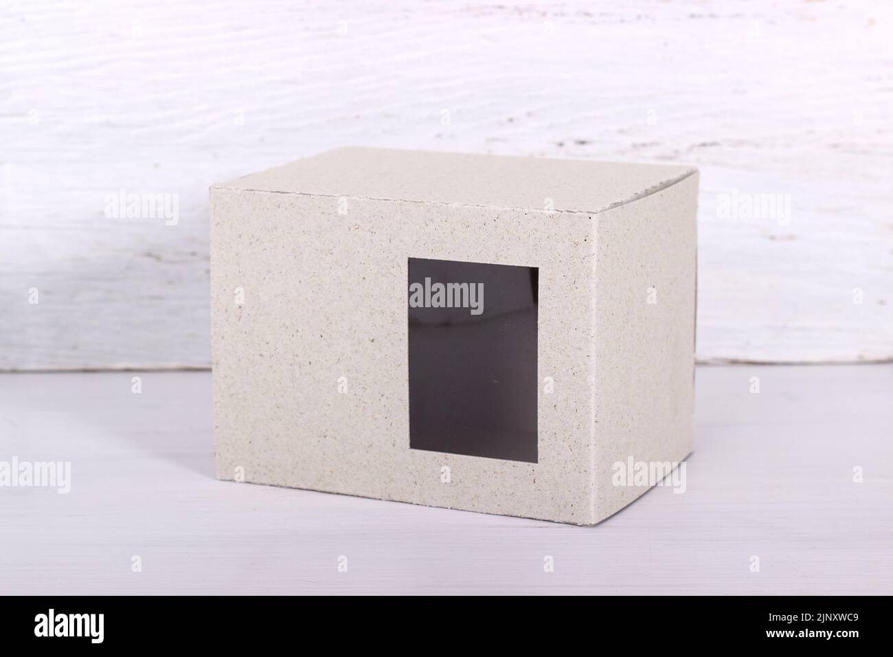 Light-colored cardboard packaging with window in front of light-colored ...