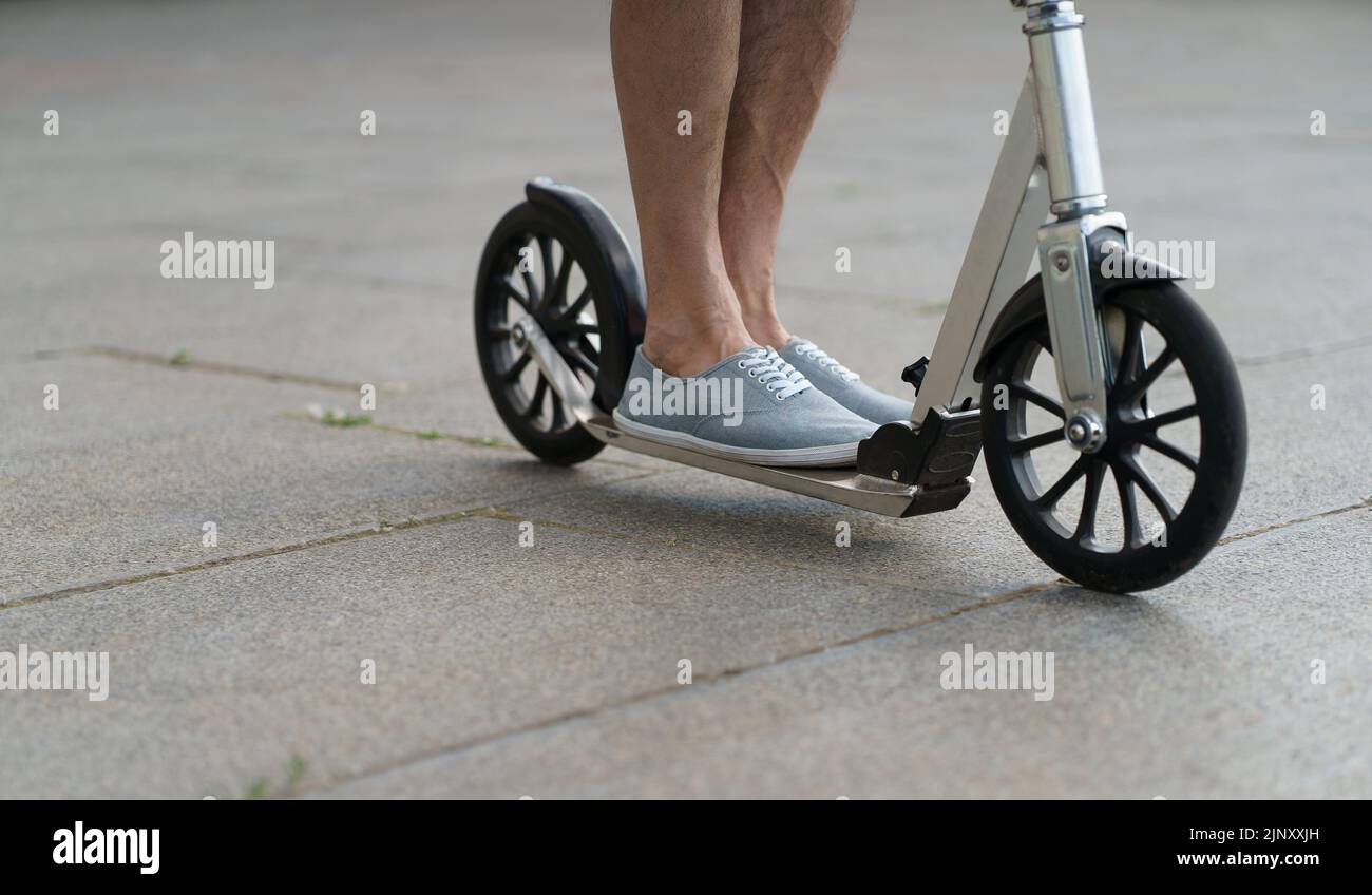 Man feet on scooter close up wearing in a sneakers shoes. Scooter with ...
