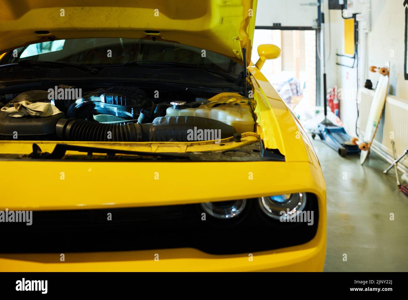 Part of car with open lid of hood standing in garage or maintenance ...
