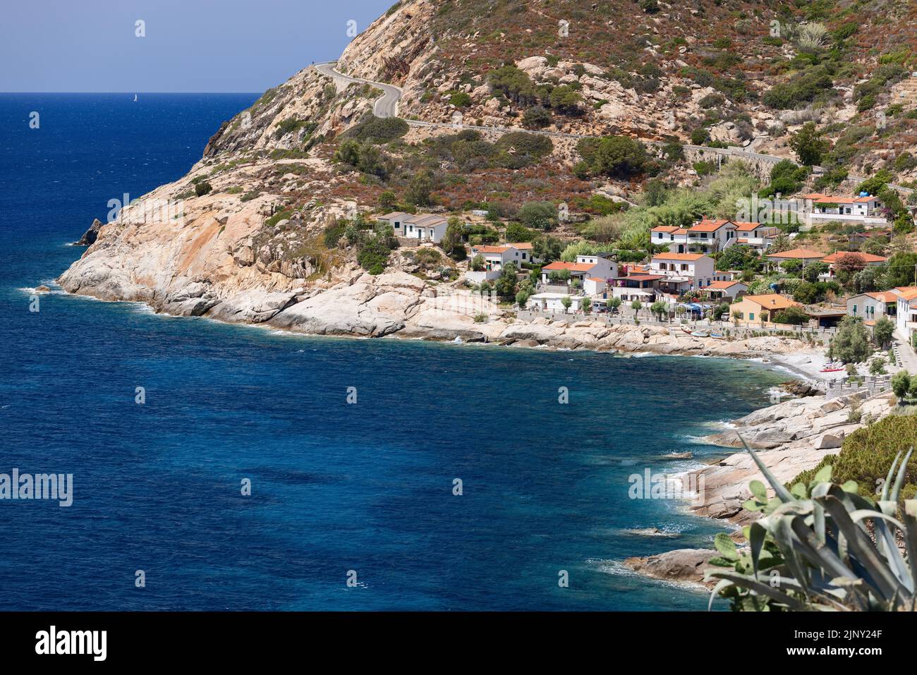 Cute little village nestled in a picturesque bay with emerald water and ...