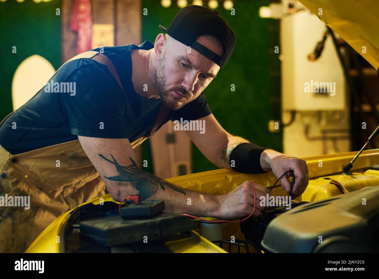 Young technician looking at numbers on display of digital multimeter ...