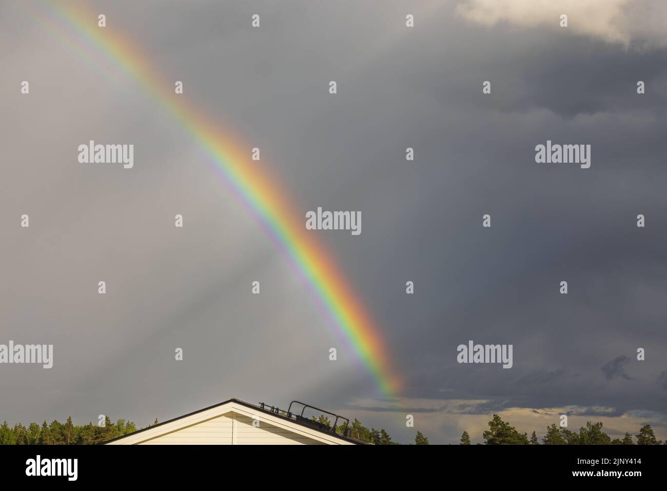 Beautiful view of rainbow after rain over roofs of pitchforks on warm ...