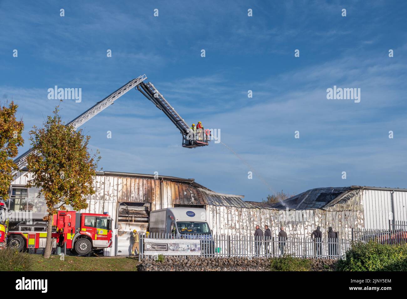 A firecrew on a high lift platform directing a jet of water into the ...