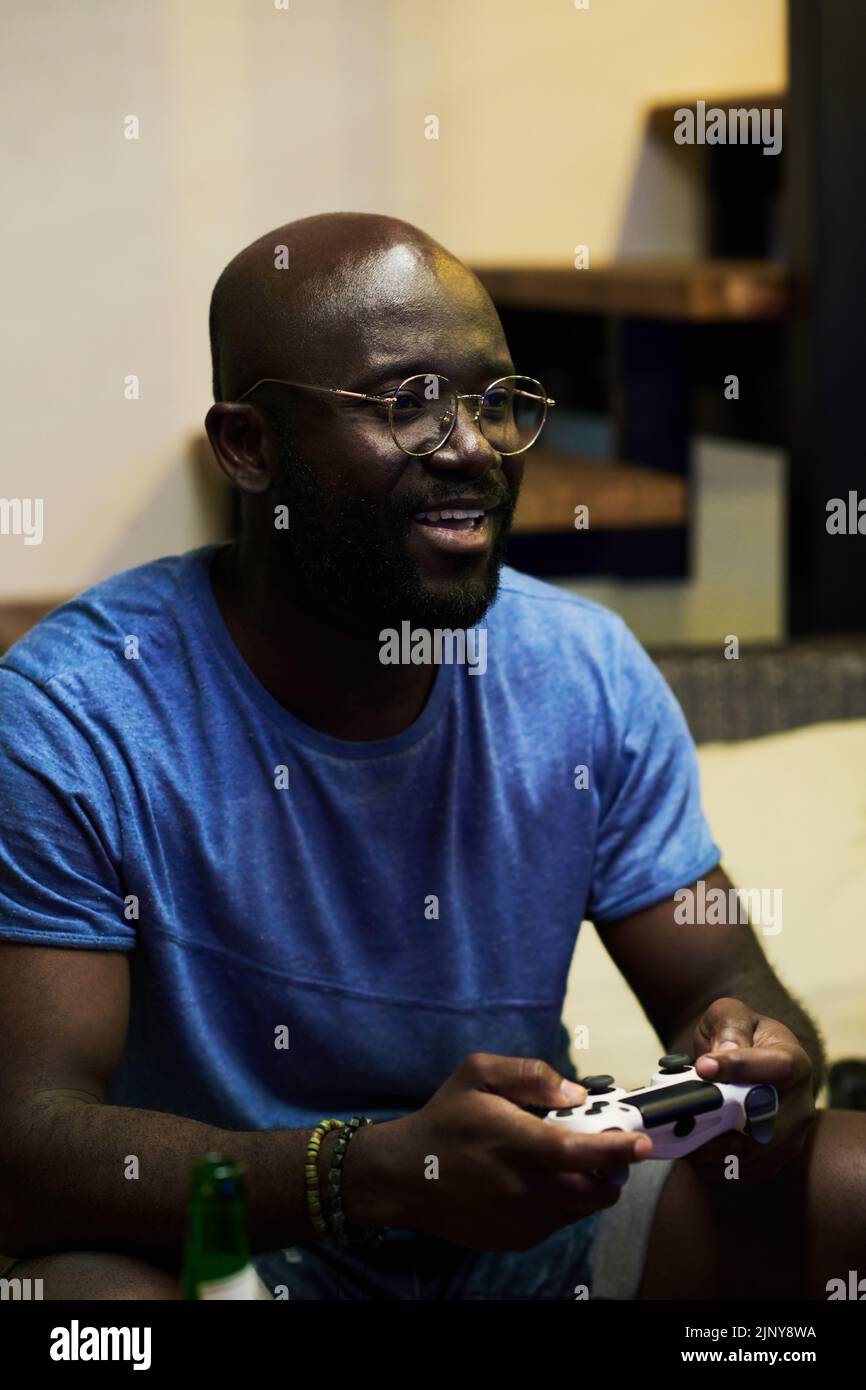 Young smiling black man in eyeglasses and blue t-shirt pressing buttons ...