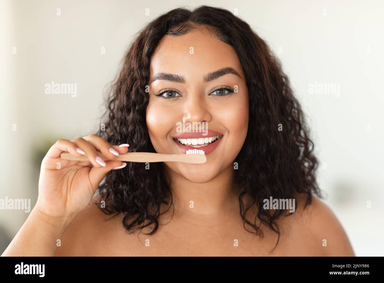 Healthy teeth and care. Happy black plus size lady brushing teeth with ...