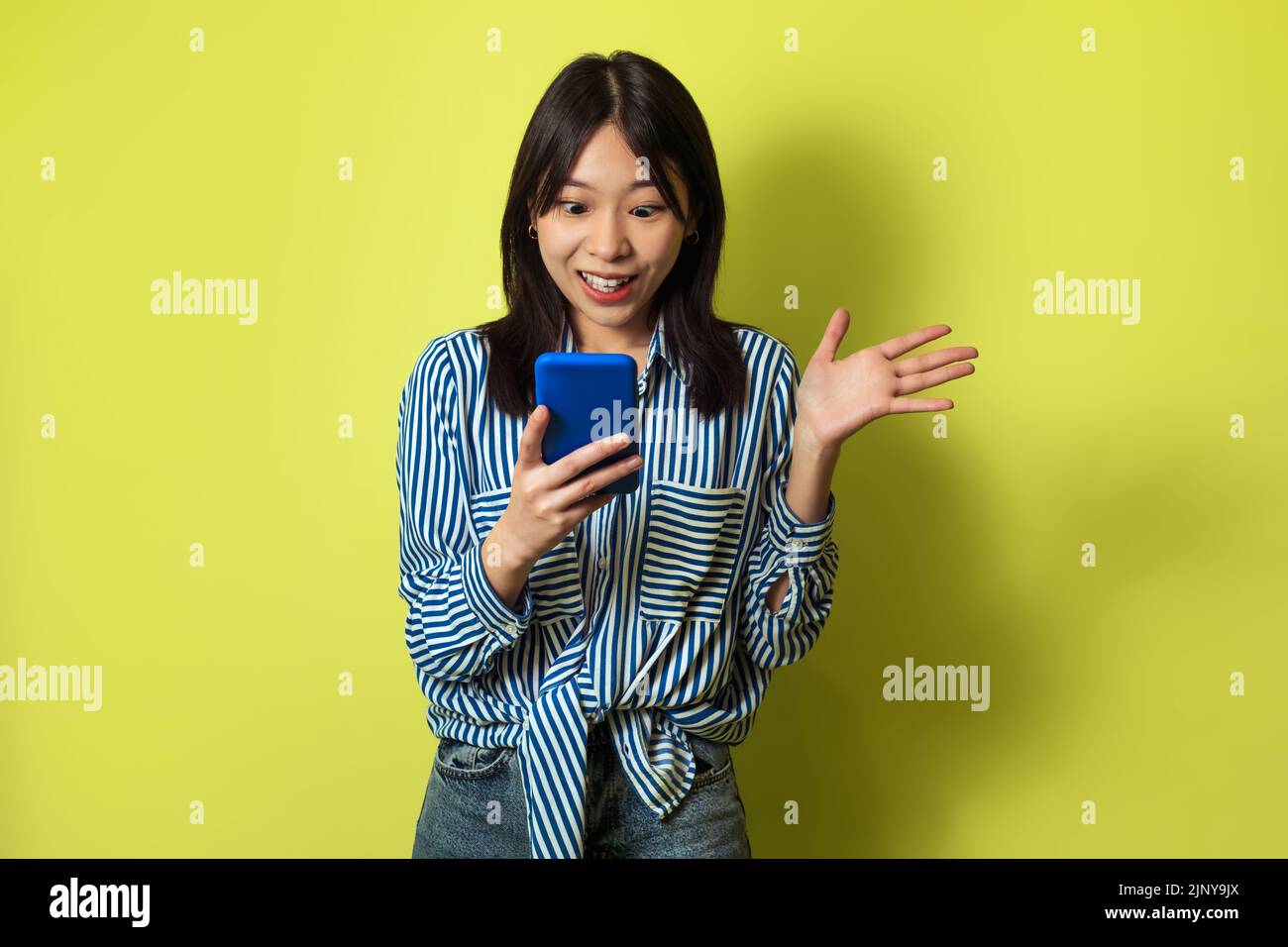 Excited Korean Lady Using Mobile Phone Standing Over Yellow Background ...