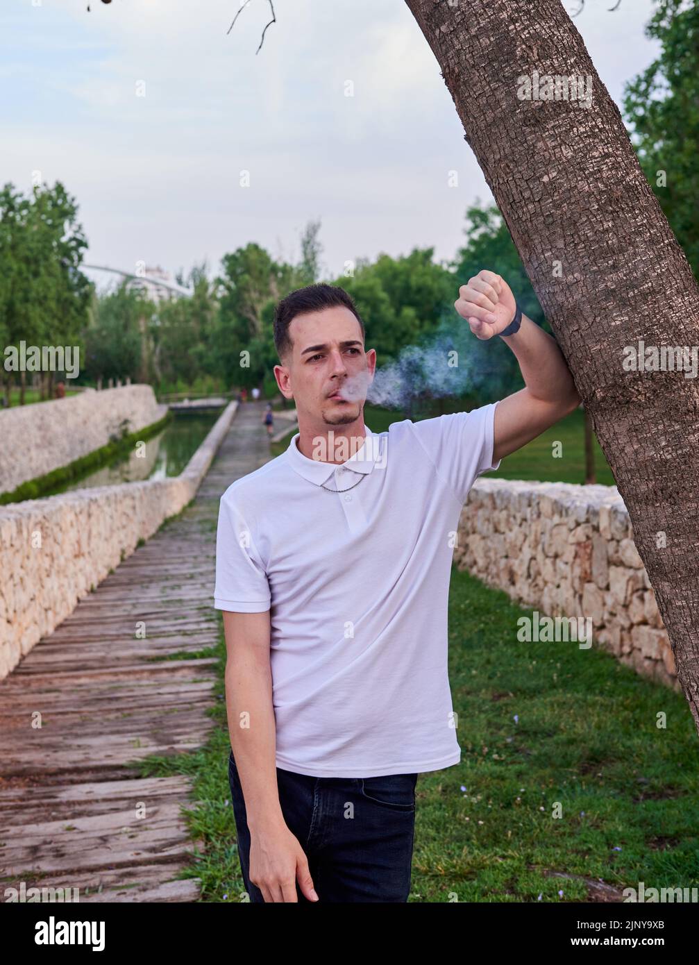 A young boy smoking while leaning against a tree Stock Photo - Alamy