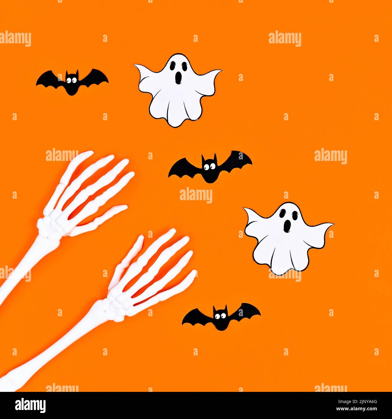 Skeleton hands with bats and ghosts on orange background. Flat lay ...